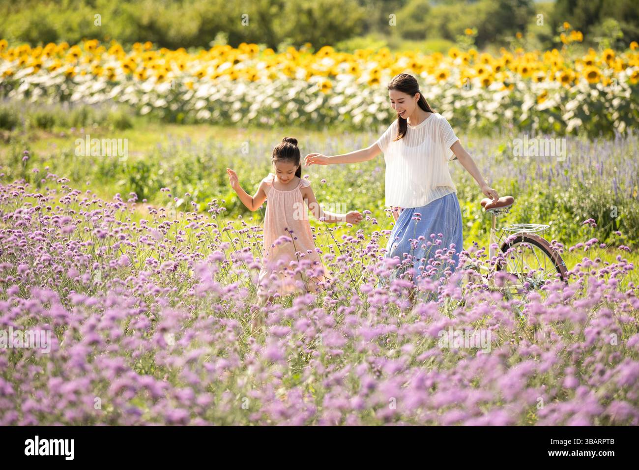 Chinese mother and daughter playing while running in flower field ...