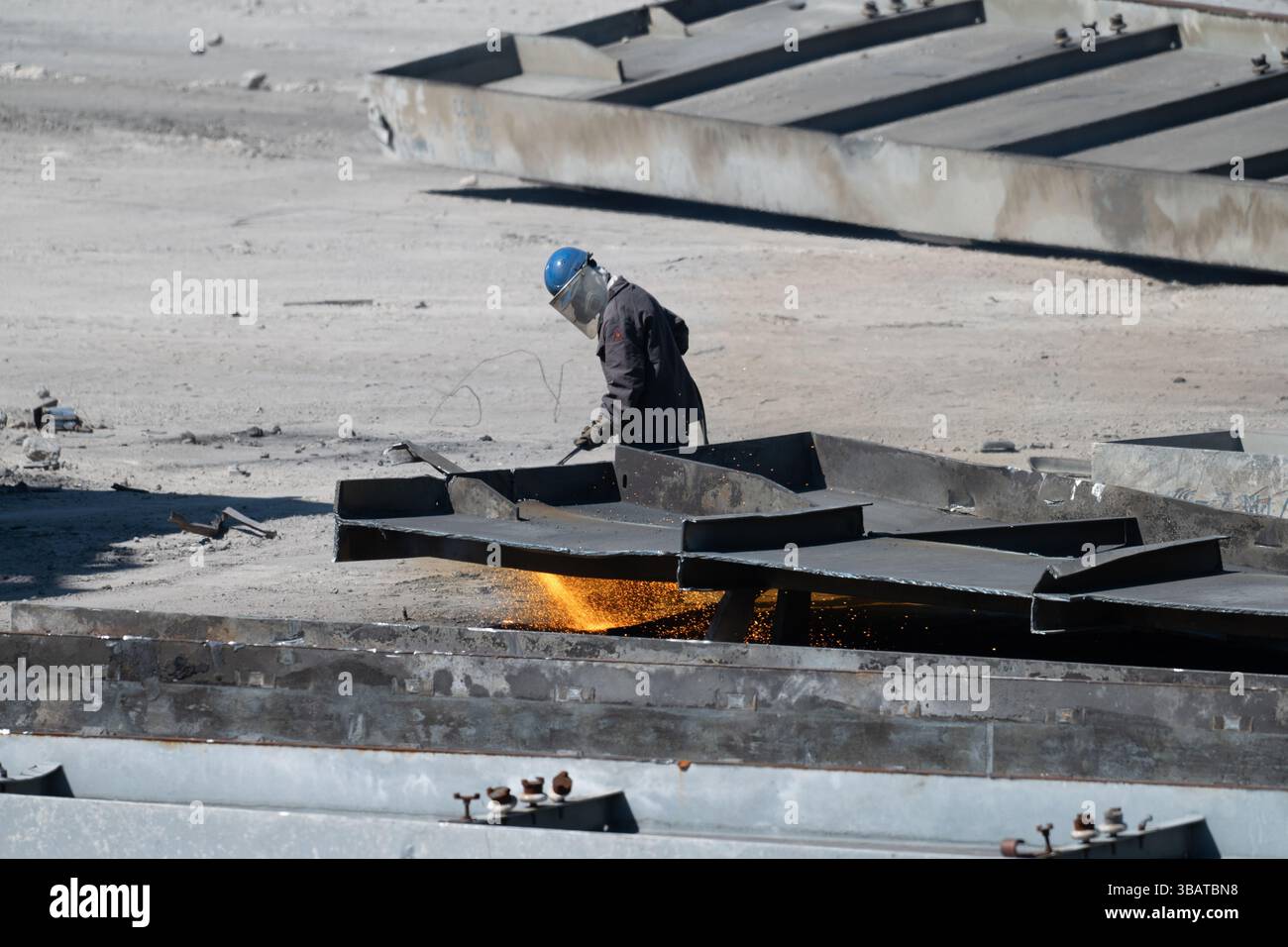 A worker cuts steel plates with a cutting torch during demolition work ...