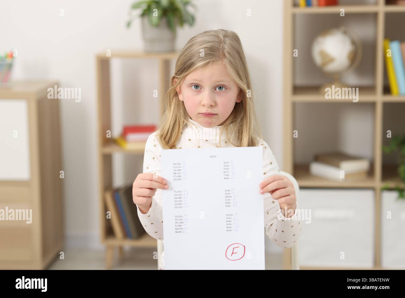 School grade. Sad girl holding answer sheet with letter F indoors Stock ...