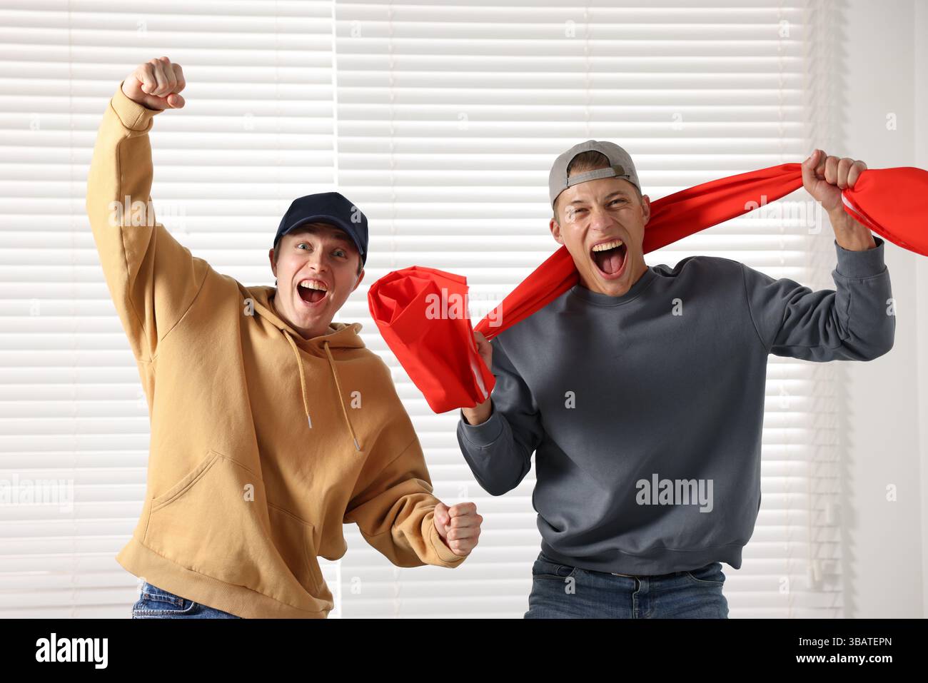 Emotional sports fans with flag near window indoors Stock Photo - Alamy