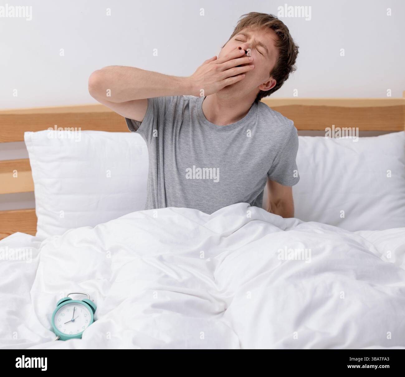 Man yawning in bed indoors. Good morning Stock Photo - Alamy