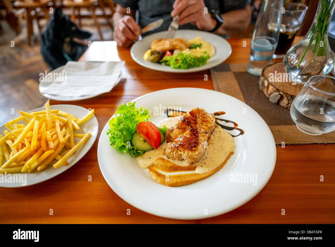 Dining in restaurant,table with plate with food (pork steak with ...