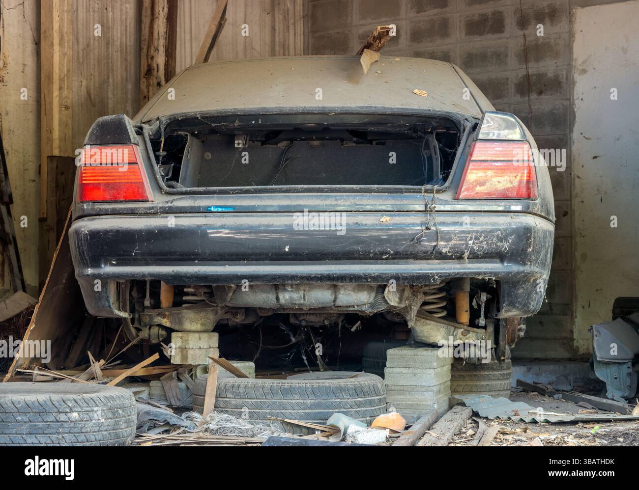 Damaged car without rear wheels in a dusty garage Stock Photo - Alamy
