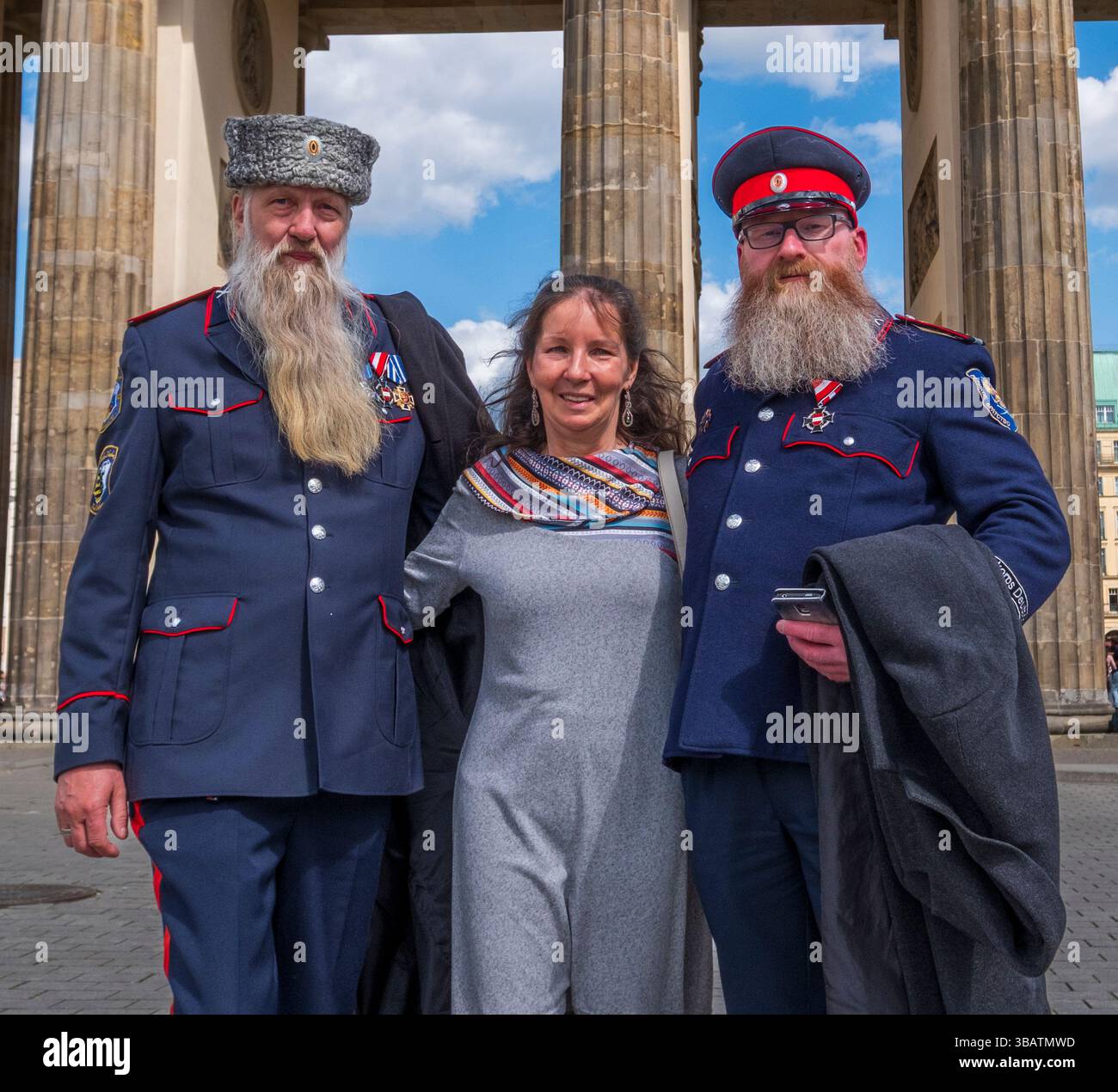 A woman poses for a photo with two men dressed in Cossack uniforms in ...