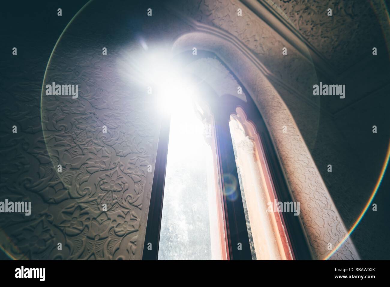 Sunlight streaming through an ornate arched window with intricate ...