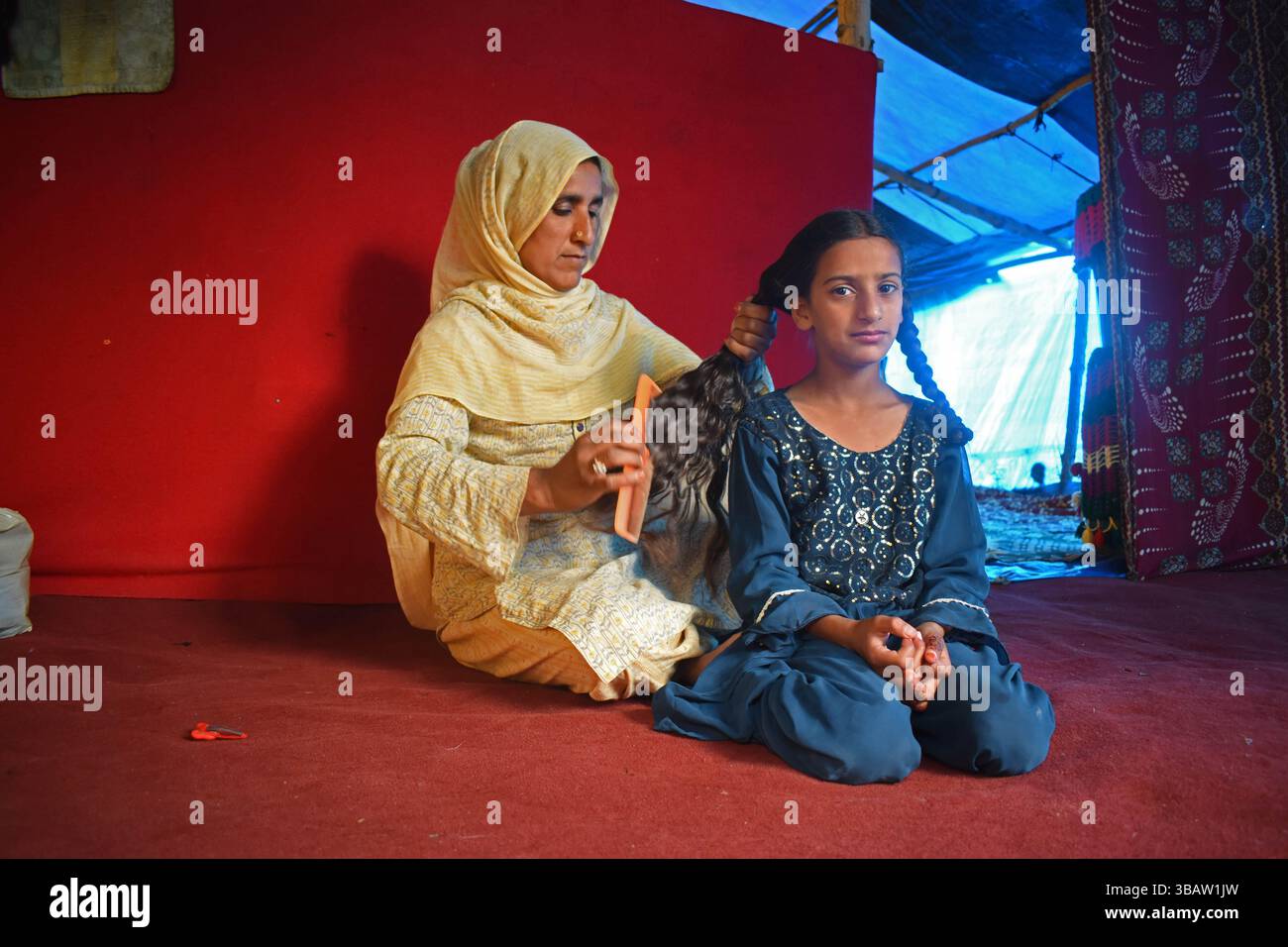 A tribal woman and her daughter stand at the entrance of a makeshift ...
