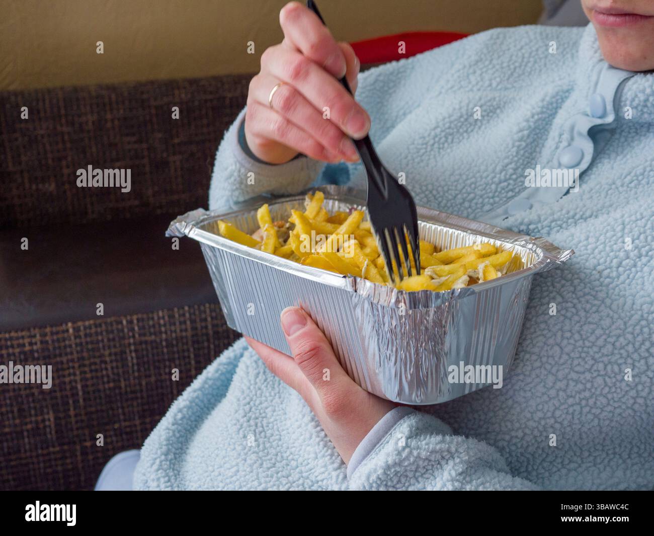 Cozy woman relaxing in pajamas, munching kebab and fries from takeout ...
