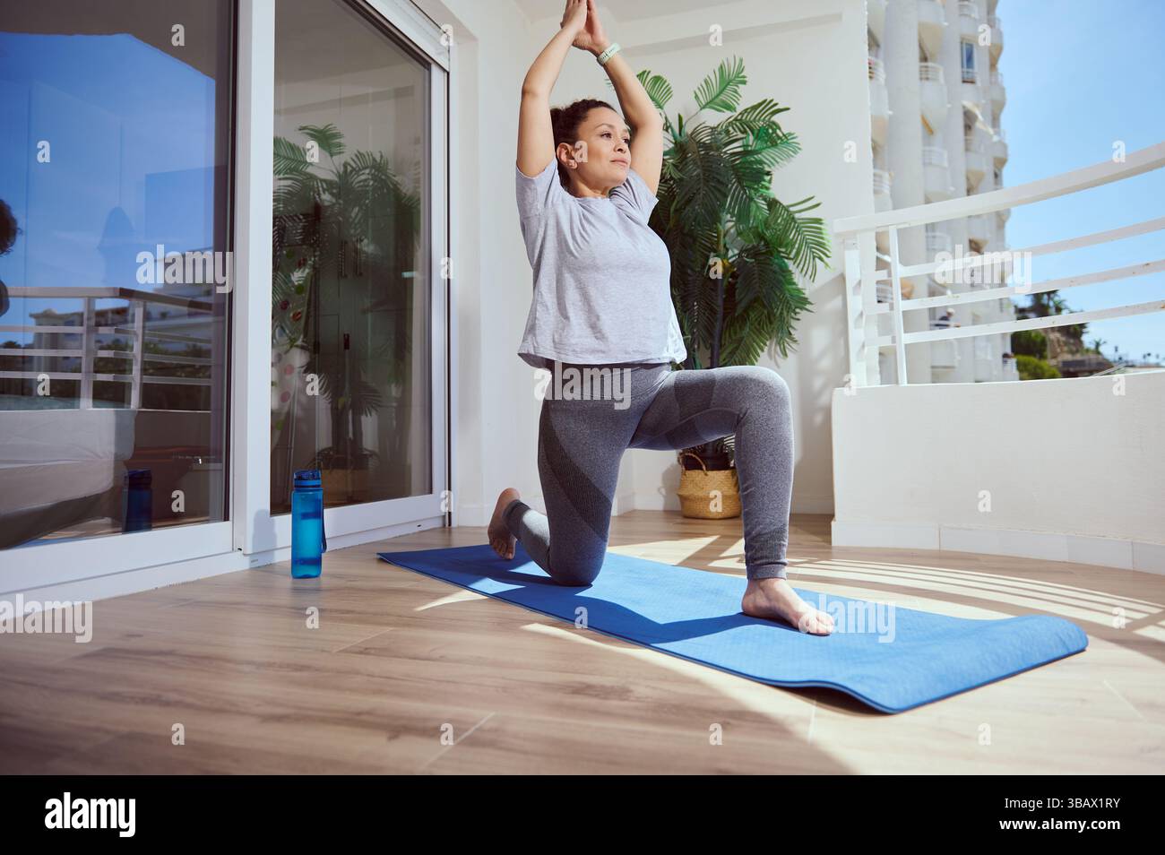 A person practices a yoga pose on a terrace, showcasing healthy living ...