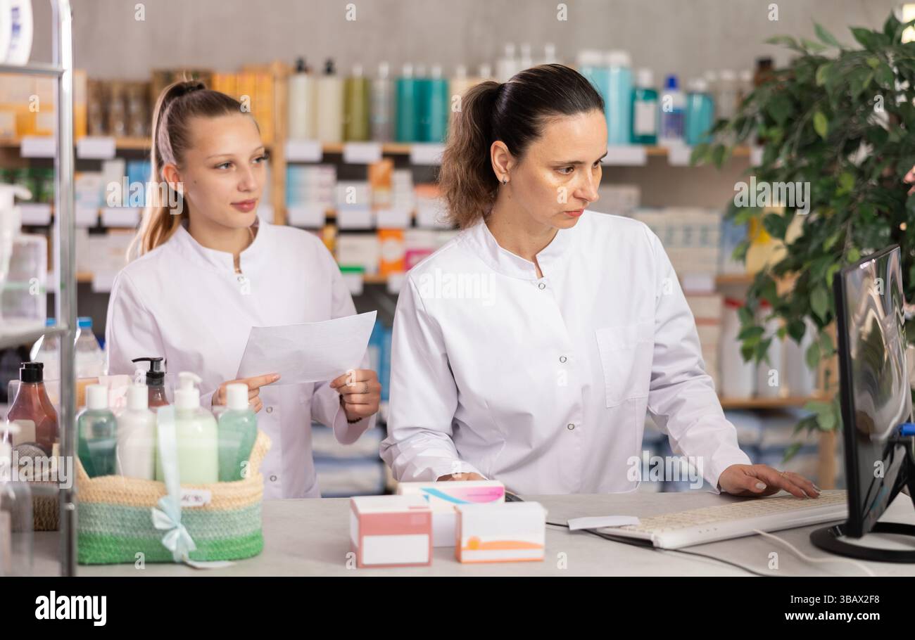 Two female pharmacists checking prescription on computer Stock Photo ...