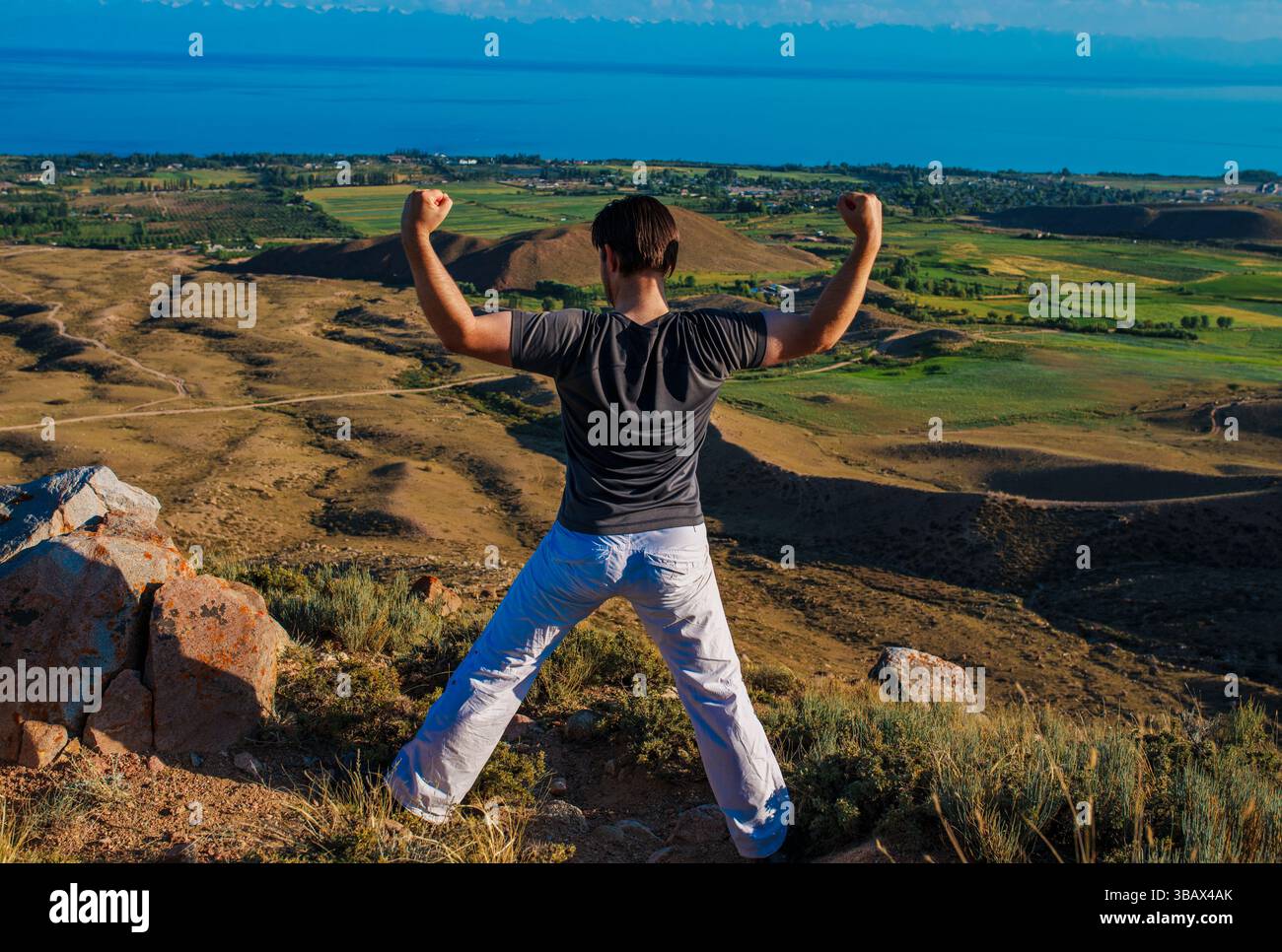 Young man traveler showing his strength on top of the mountain Stock ...