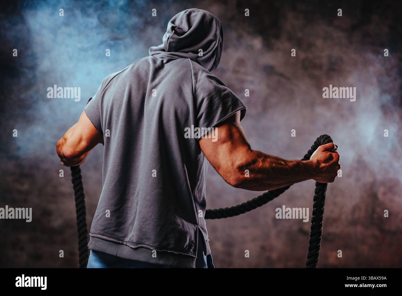 Strong man bodybuilder with hood holds the rope Stock Photo - Alamy