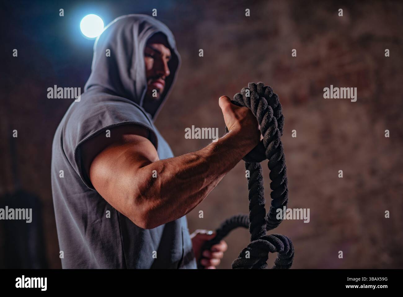 Strong man bodybuilder with hood holds the rope Stock Photo - Alamy