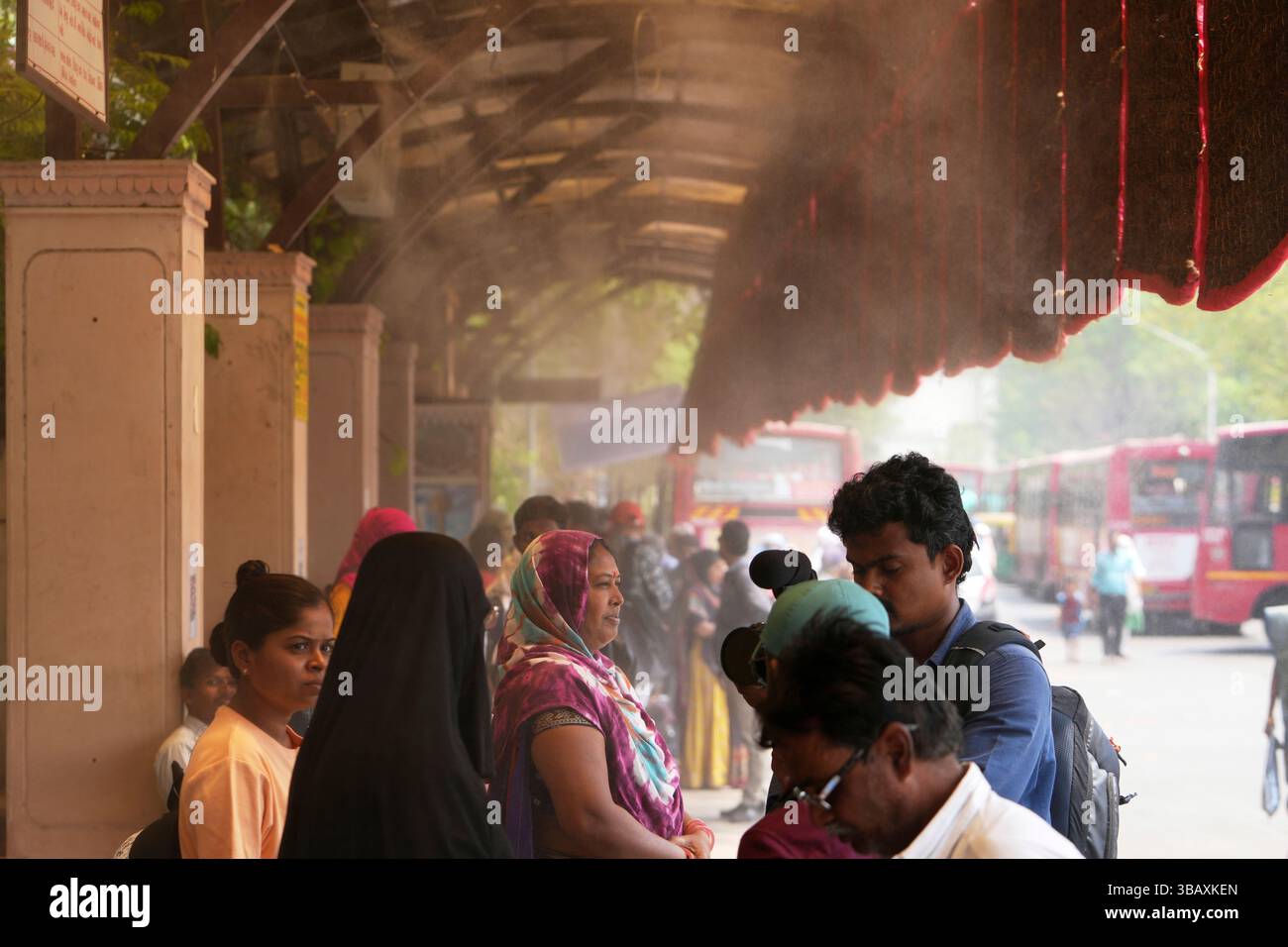 People wait for a bus at a cool bus stop in Ahmedabad, India, Wednesday ...