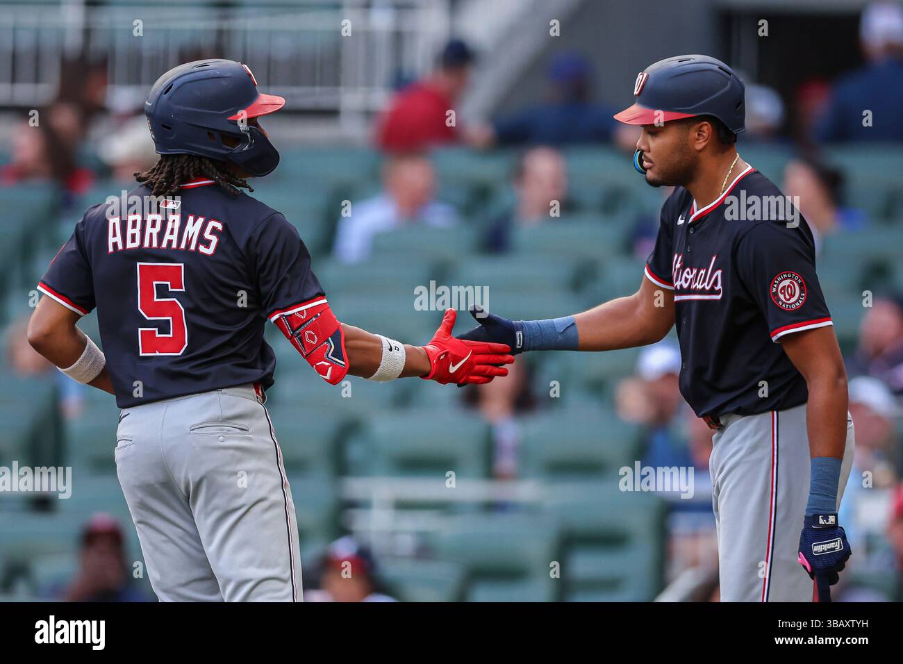 Washington Nationals' CJ Abrams (5) high-fives James Wood, right, after ...