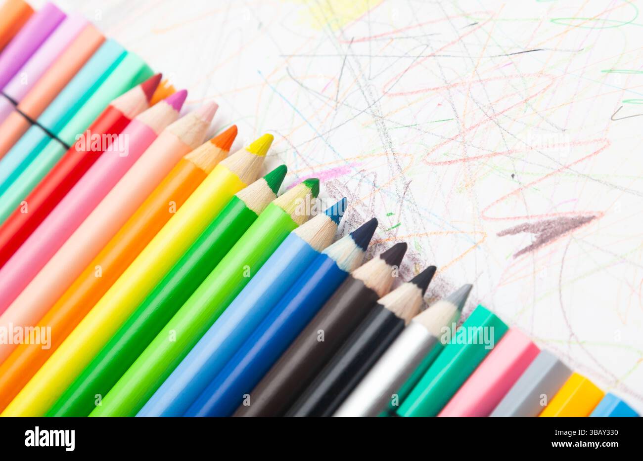 Multi-colored pencils lie on white paper drawn with multi-colored ...