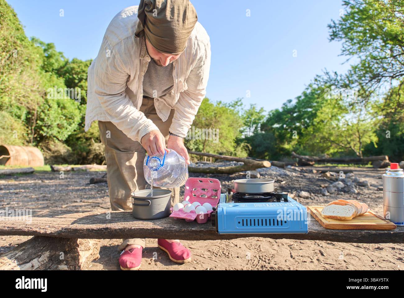 Hispanic man pouring drinking water into a pot as part of the process ...