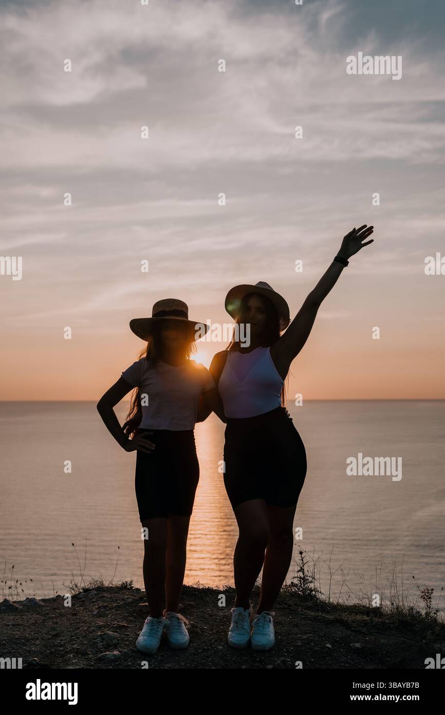 Silhouettes of Two Women in Hats on a Cliffside at Sunset Stock Photo ...