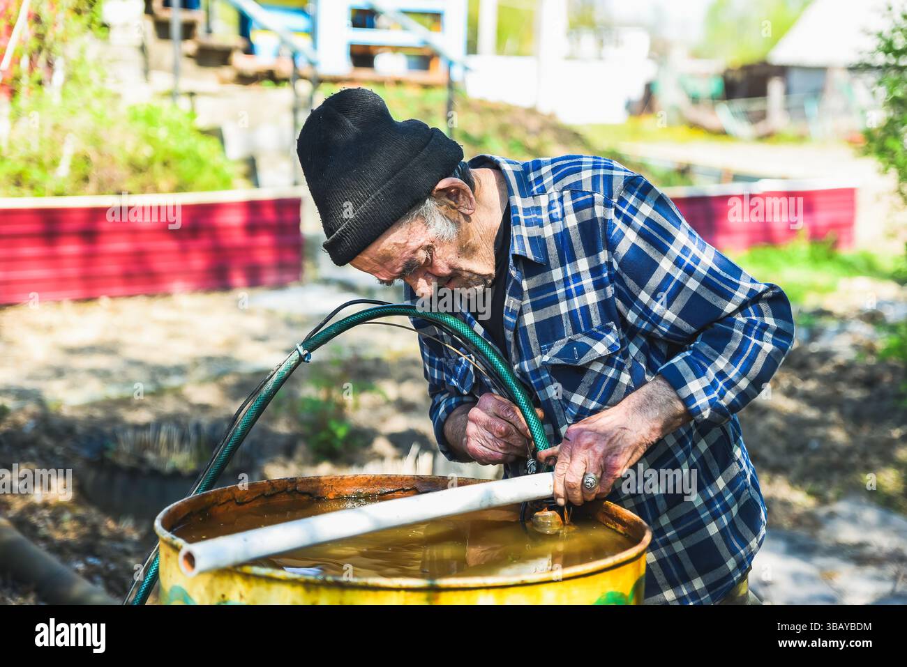 Elderly Russian man in a village working with a drainage pump ...