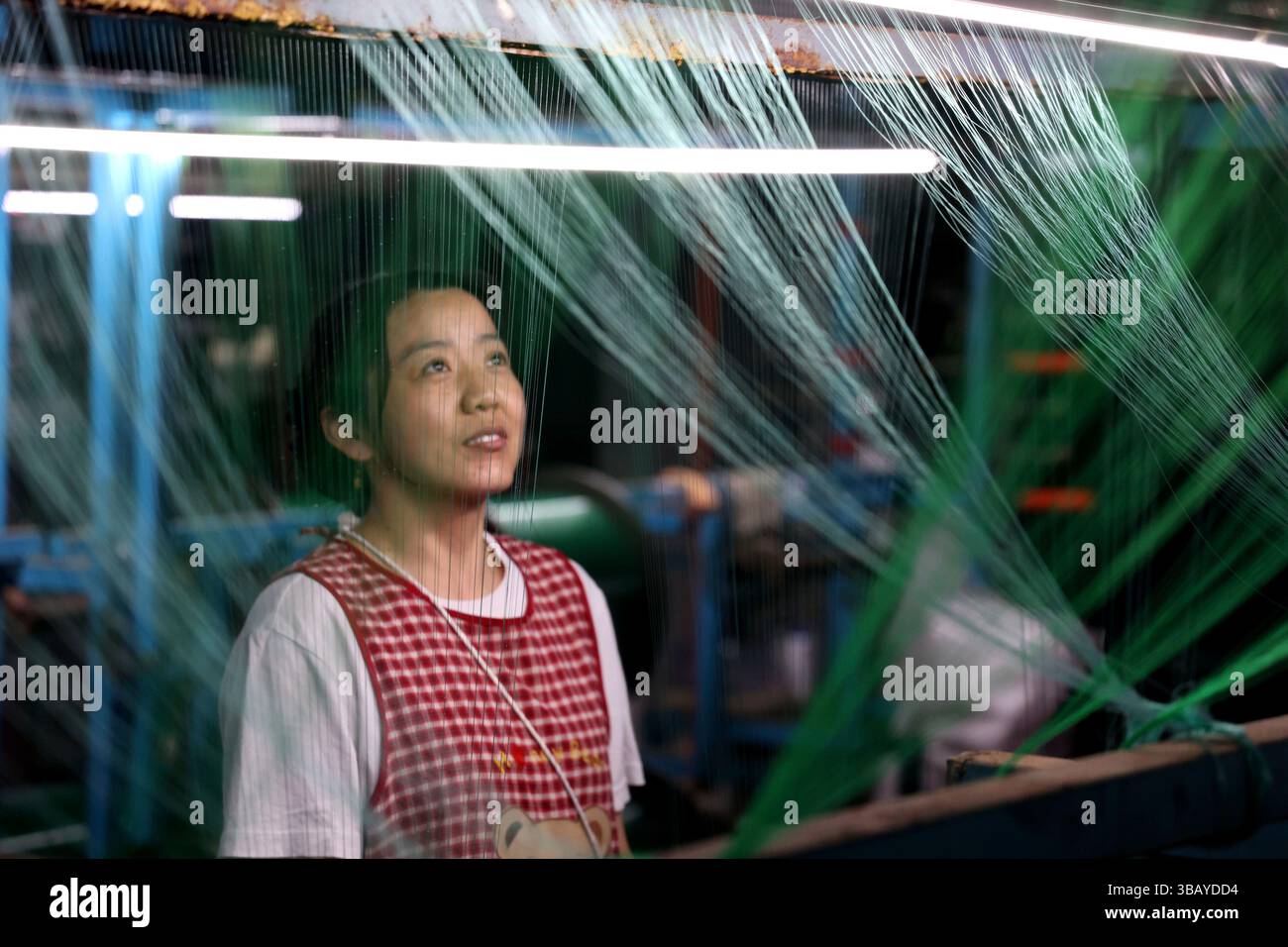 A woman works in a factory weaving nets in Huimin county in east China ...