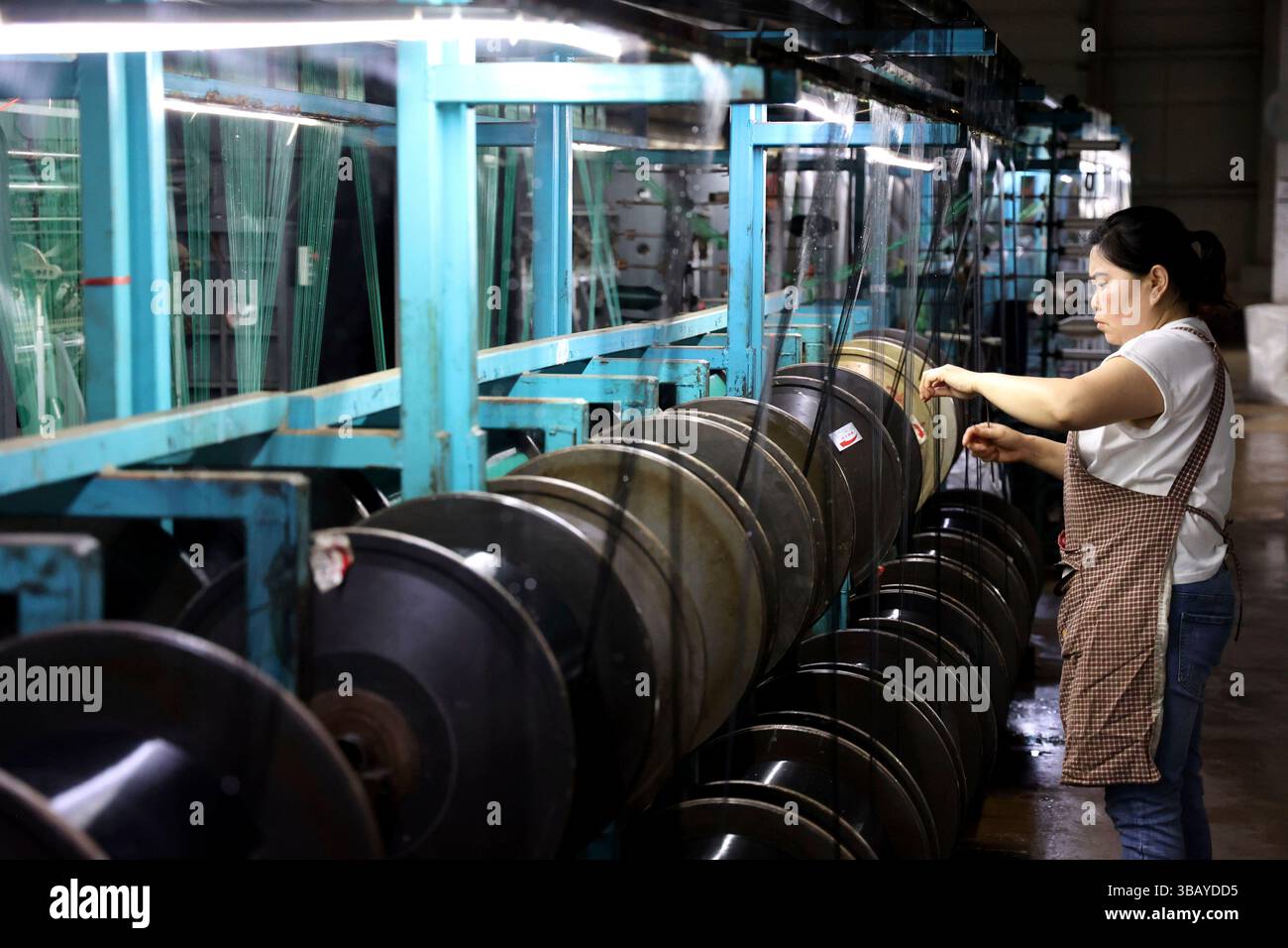 A woman works in a factory weaving nets in Huimin county in east China ...