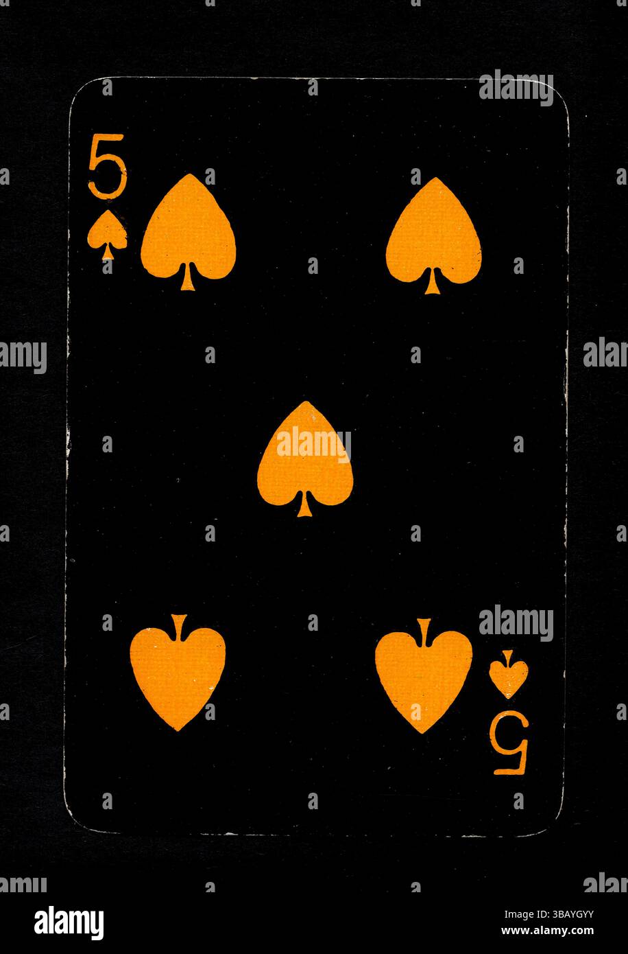 A vintage playing card in the suit of spades isolated on a black ...