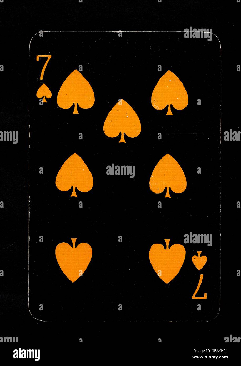 A vintage playing card in the suit of spades isolated on a black ...