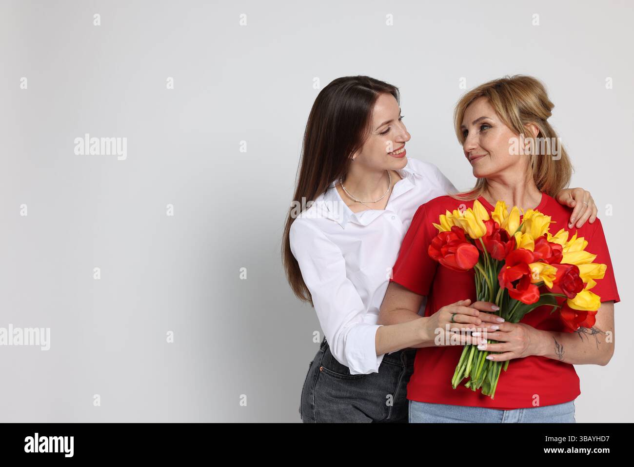 Woman giving her mother flowers on white background Stock Photo - Alamy