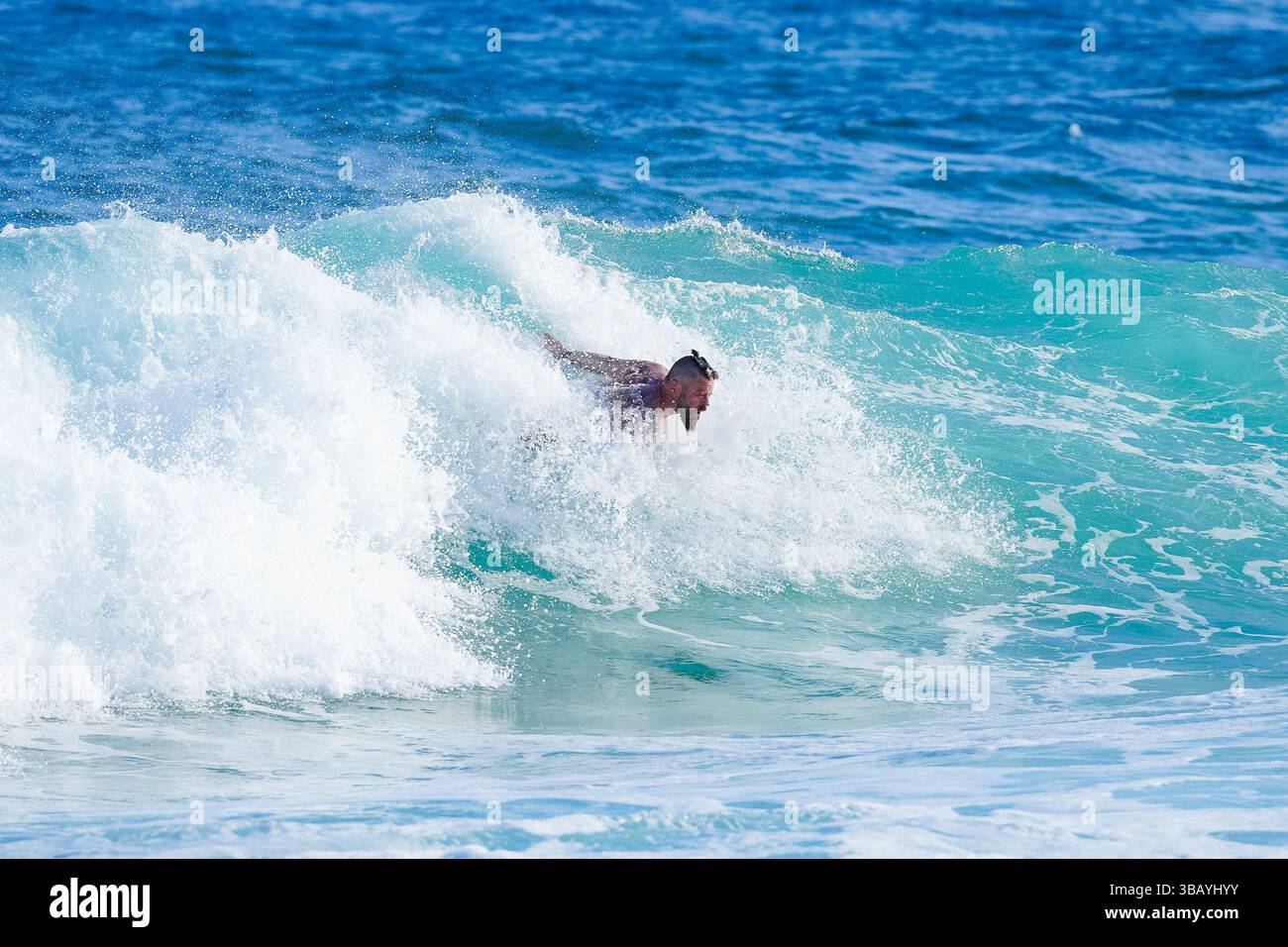Bodysurfer launches headfirst into a barreling wave with arms tucked ...