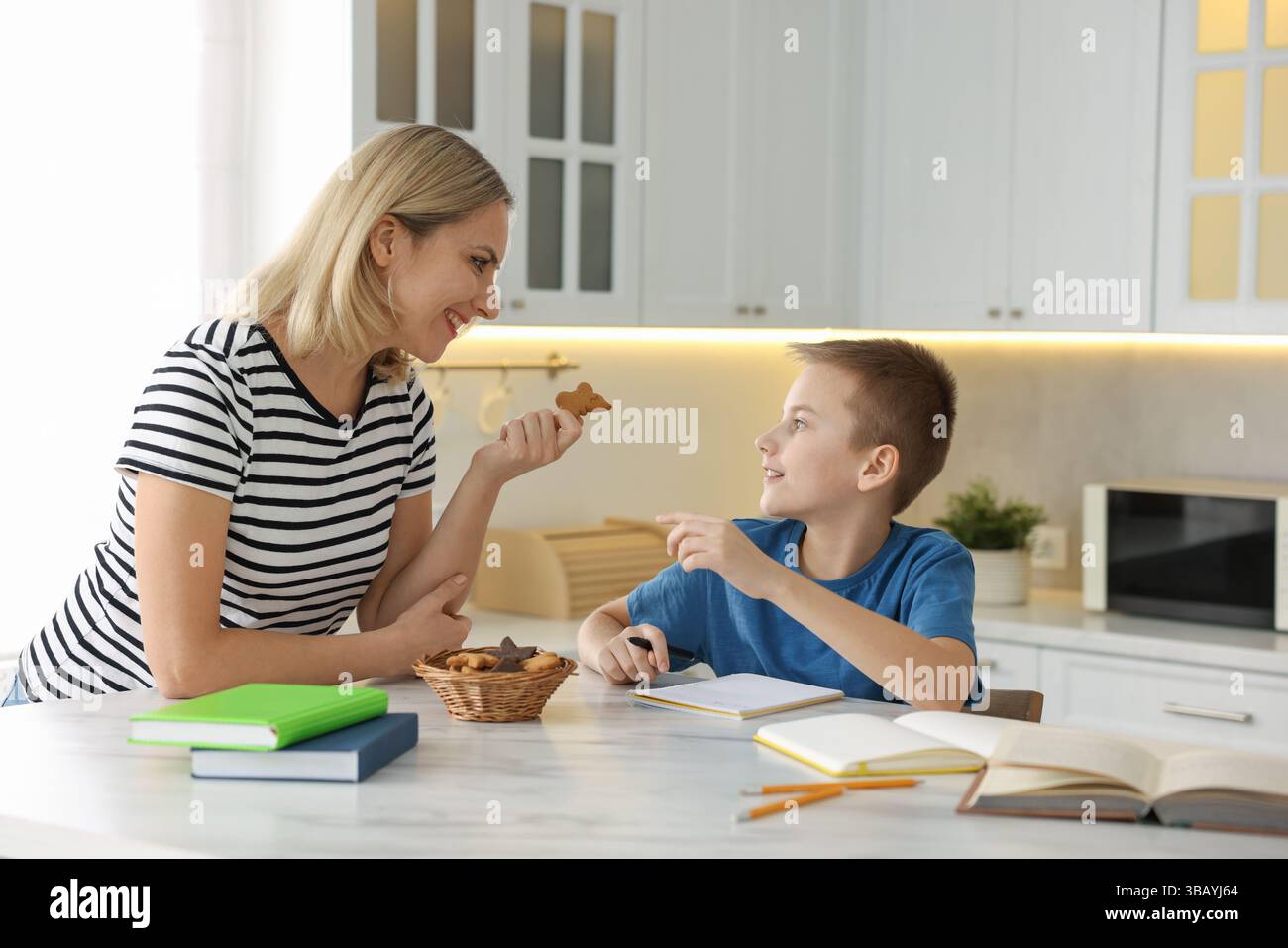 Mother and son eating cookies while doing homework indoors Stock Photo ...