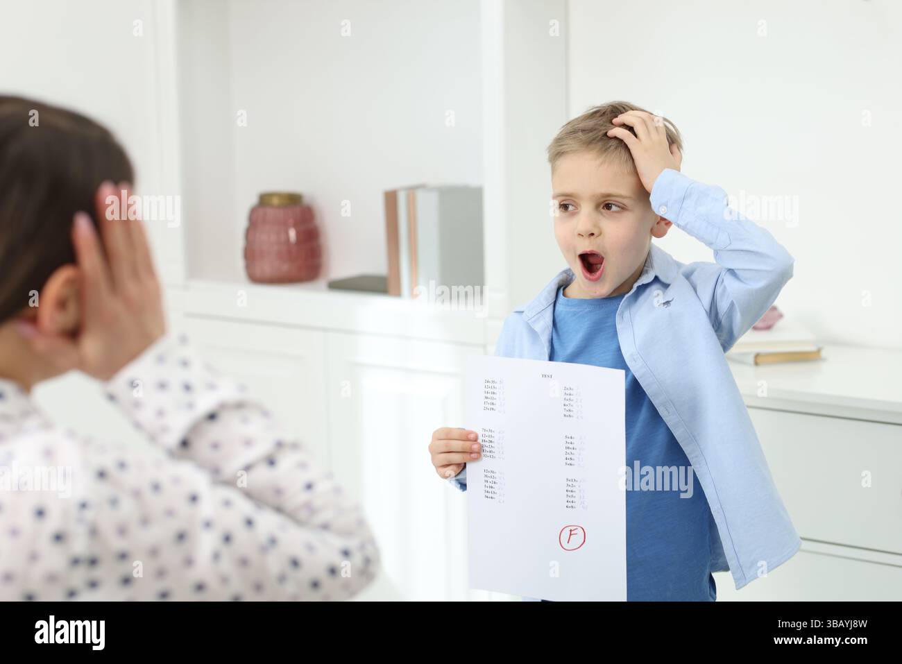 School grade. Sad boy showing answer sheet with bad mark to his mother ...