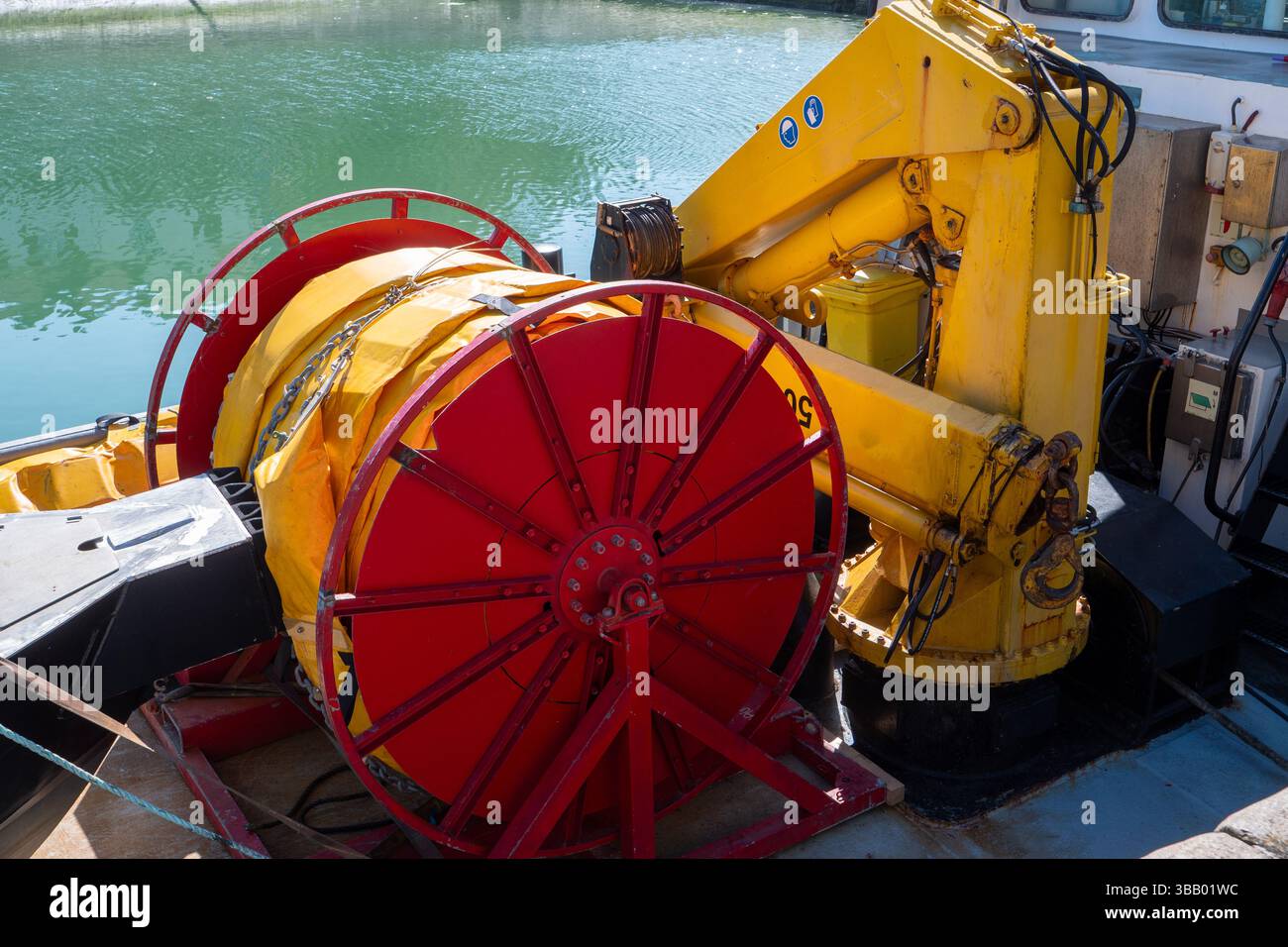Equipment of a trawler. A yellow crane is positioned next to a cable ...