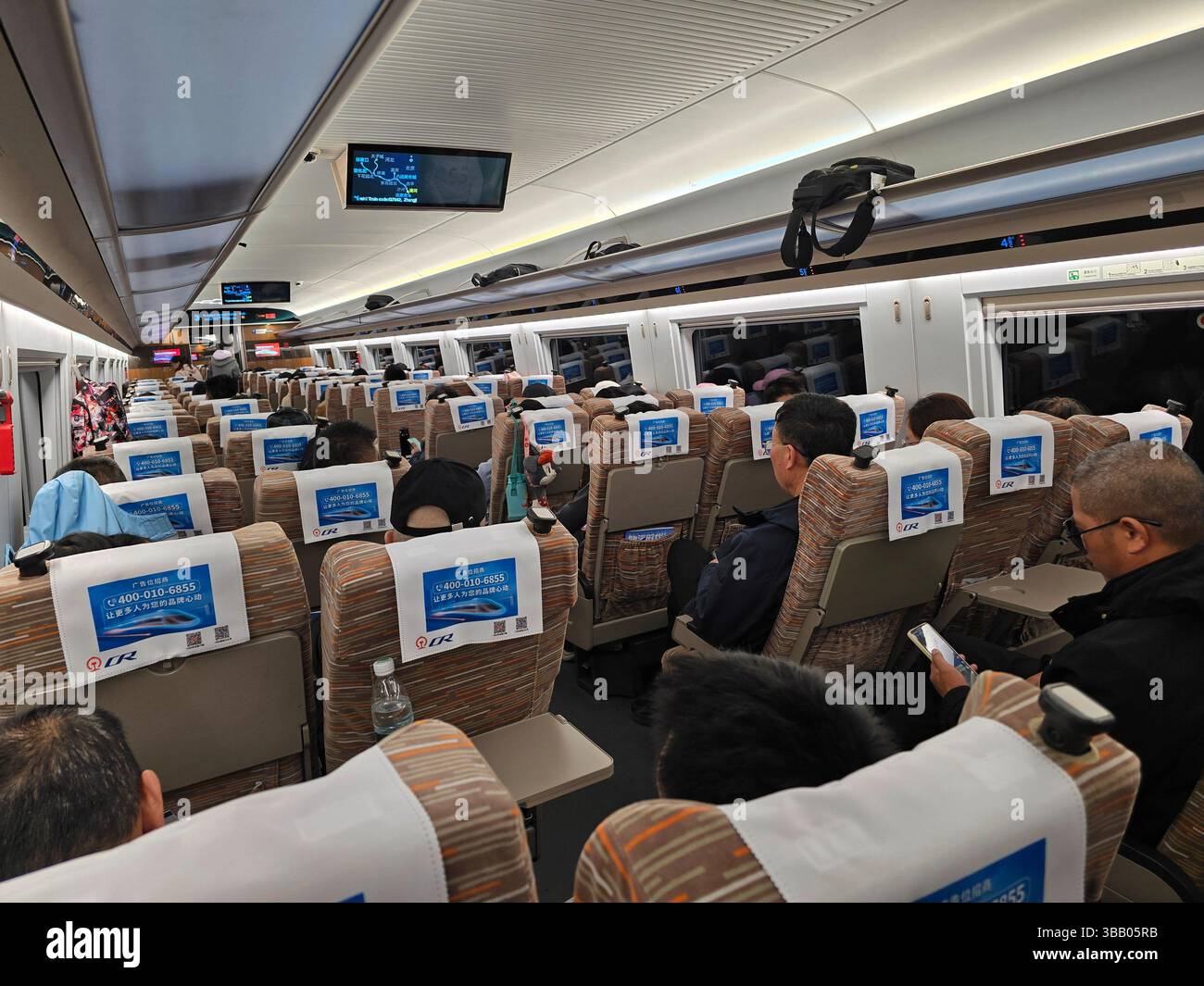 Passengers sitting inside a high-speed Chinese train with overhead ...