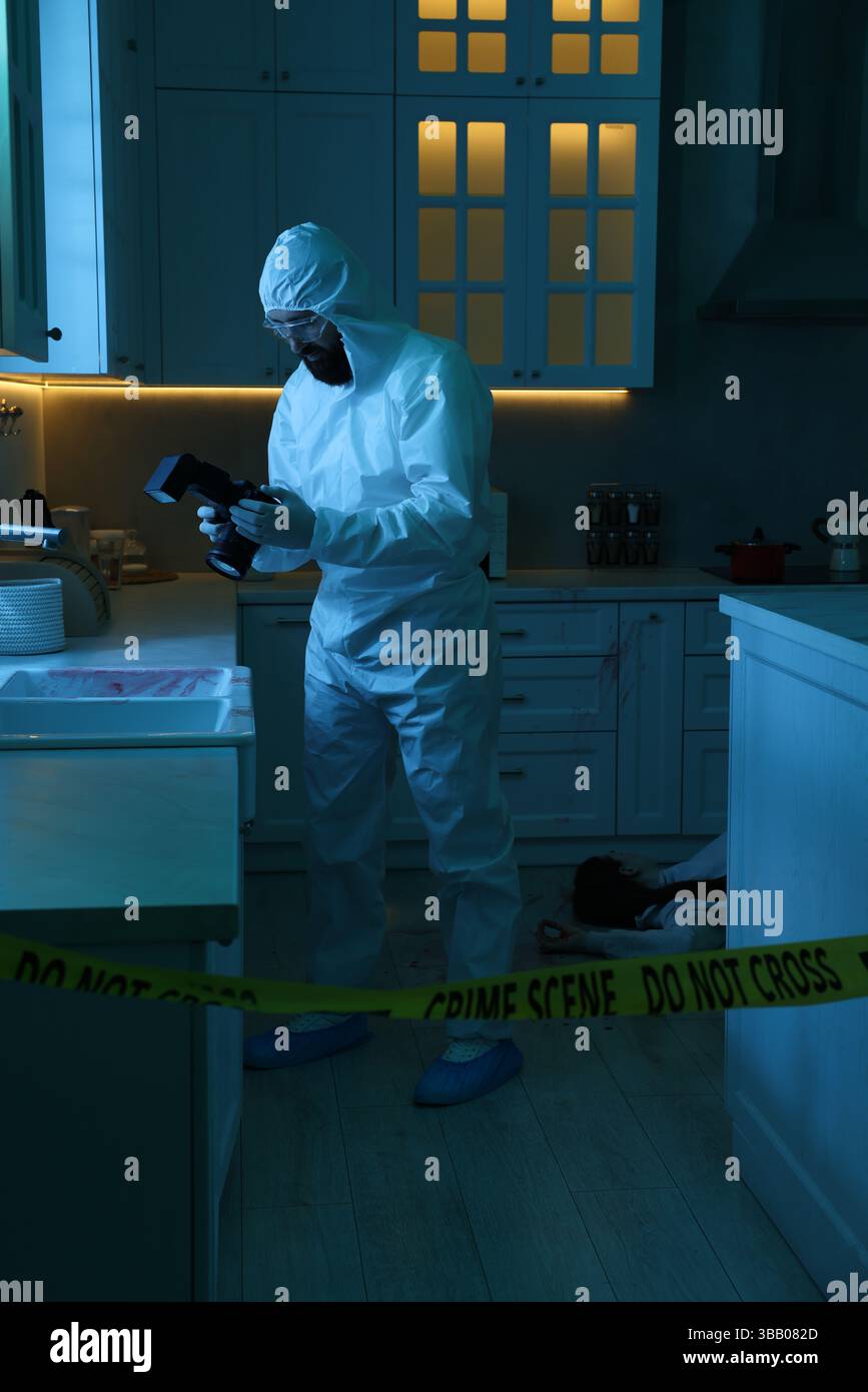 Forensic expert with camera working at crime scene in dark room Stock ...