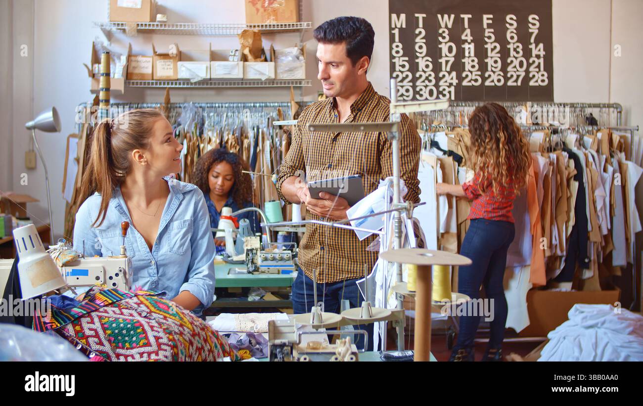 Male Supervisor With Digital Tablet Talking To Woman Using Sewing ...