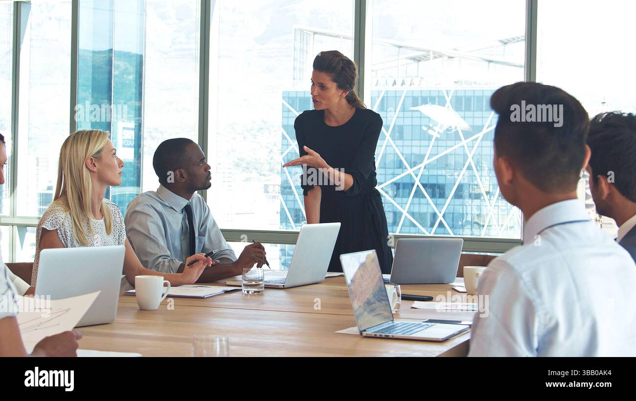 Businesswoman Giving Presentation To Business Team Sitting Around Table ...