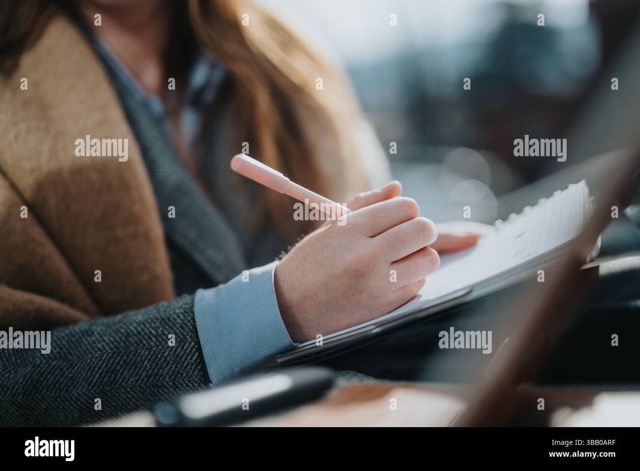 Person writing notes with a pink pen at an outdoor workspace Stock ...