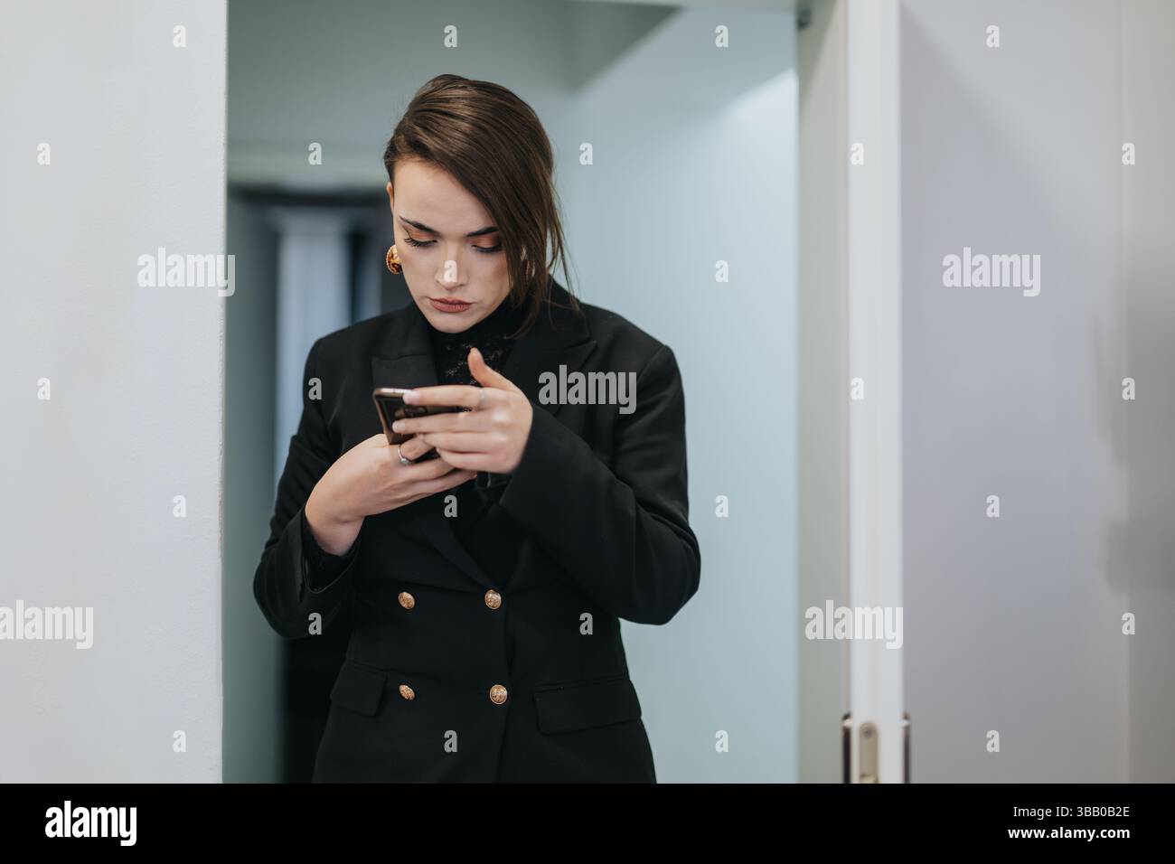 Business professional checking mobile phone in an office hallway Stock ...