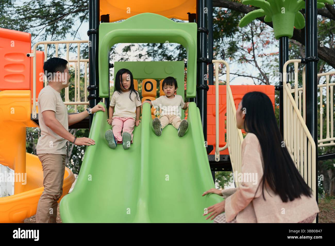 Parents watching and guiding their children as they play on a slide at ...