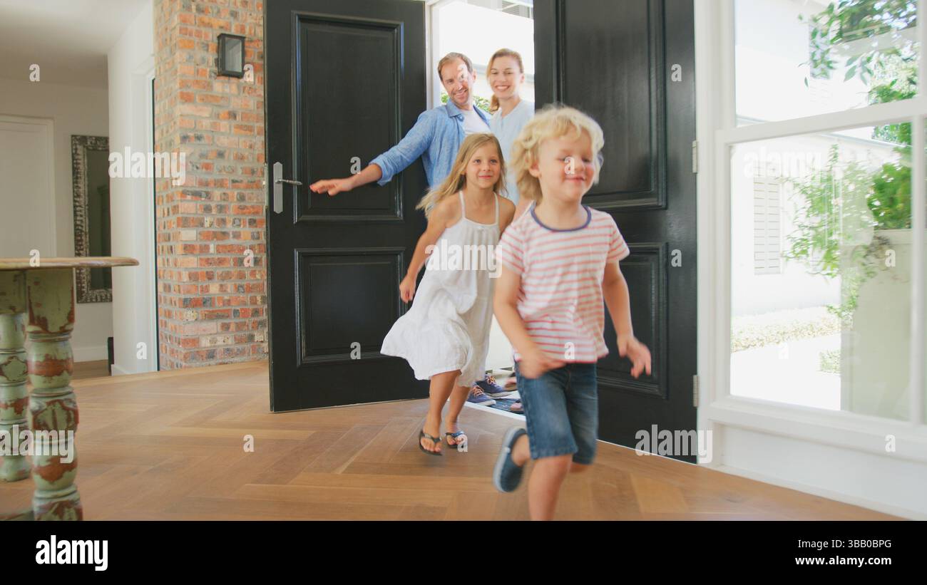 Family Returning Home With Excited Children Running Ahead Through Front ...