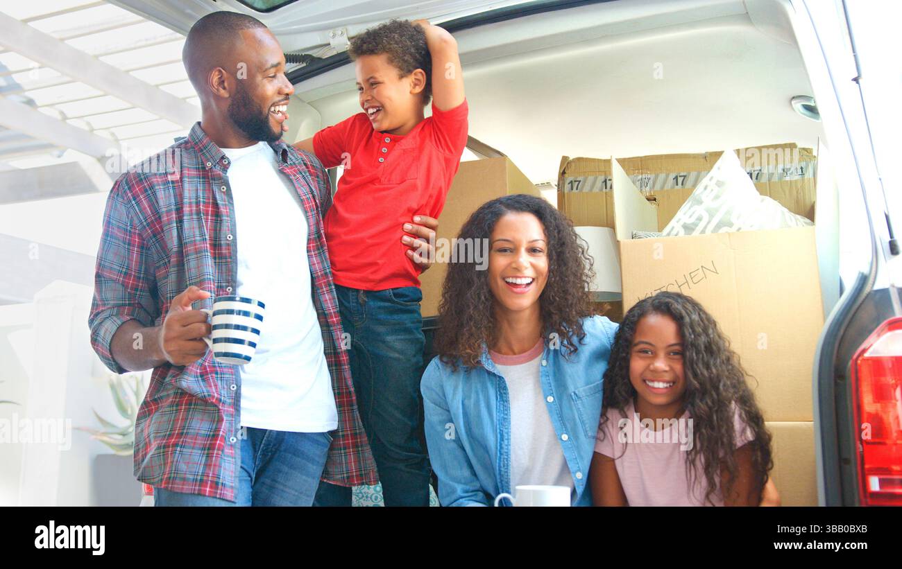Portrait Of Family Sitting In Back Of Removal Truck With Packing Boxes ...