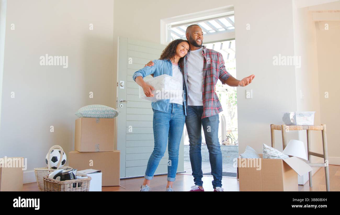 Loving Couple Standing In New Home On Moving Day Surrounded By Boxes ...