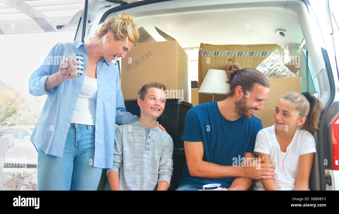 Portrait Of Family Sitting In Back Of Removal Truck With Packing Boxes ...