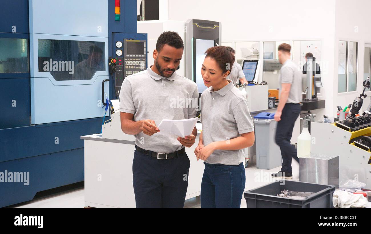 Male And Female Engineers Discussing Plans On Floor Of Engineering ...