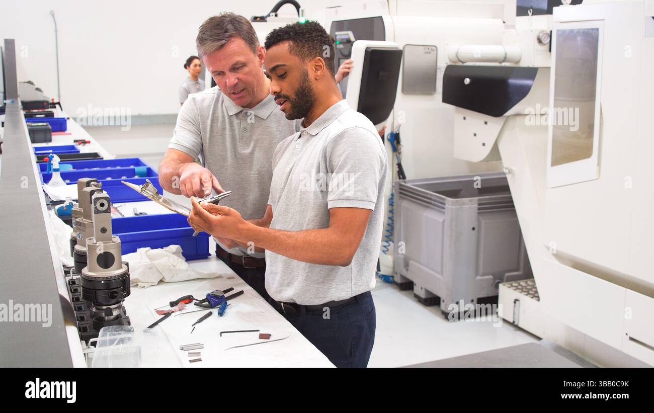 Engineer And Male Apprentice Measuring Components In Hi Tech ...