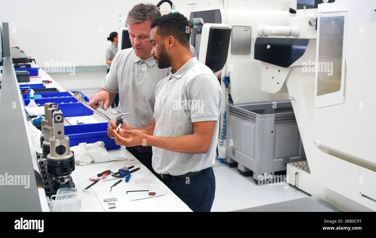 Engineer And Male Apprentice Measuring Components In Hi Tech ...