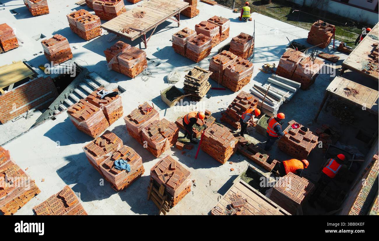 Bricklaying and construction workers at a construction site. An aerial ...