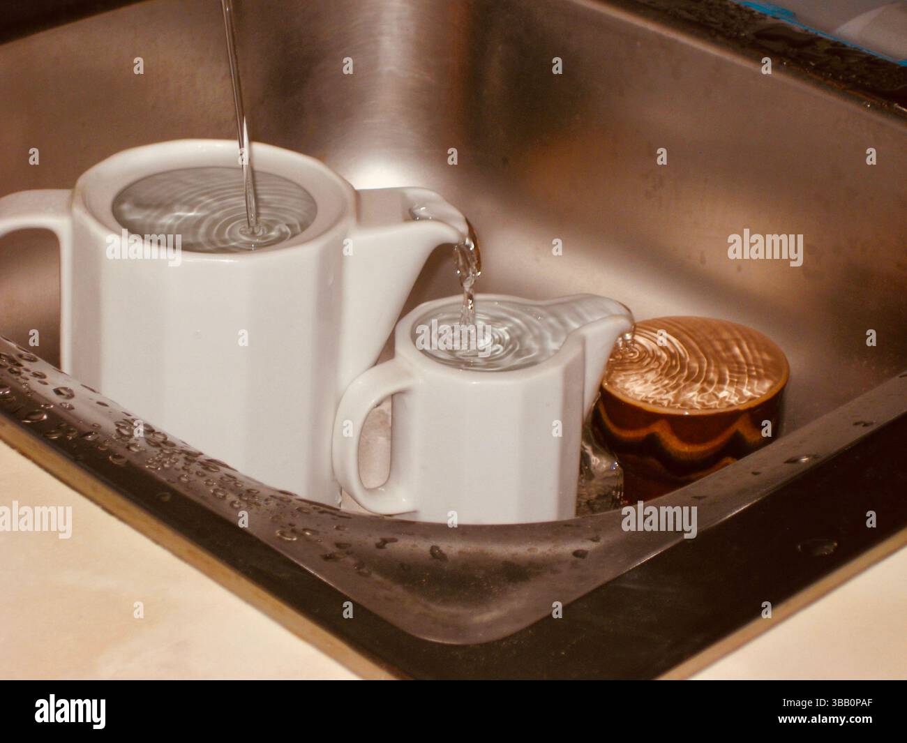 Kitchen teapots being filled incorrectly with water in a sink Stock ...