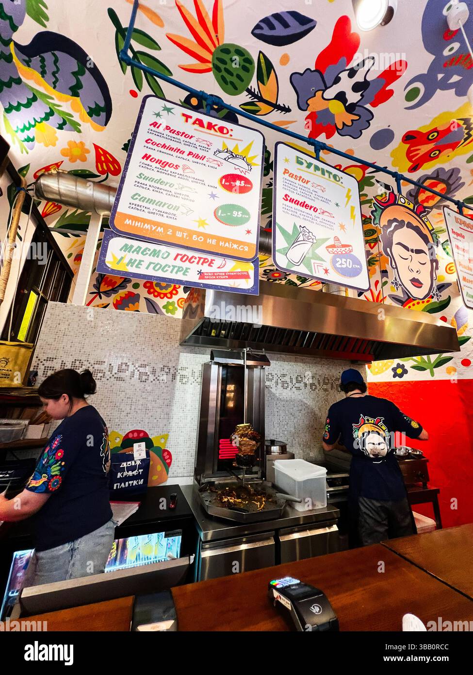 Lviv, Ukraine - May 14, 2025: Lively taco restaurant with vivid decor, a menu board, and food ...