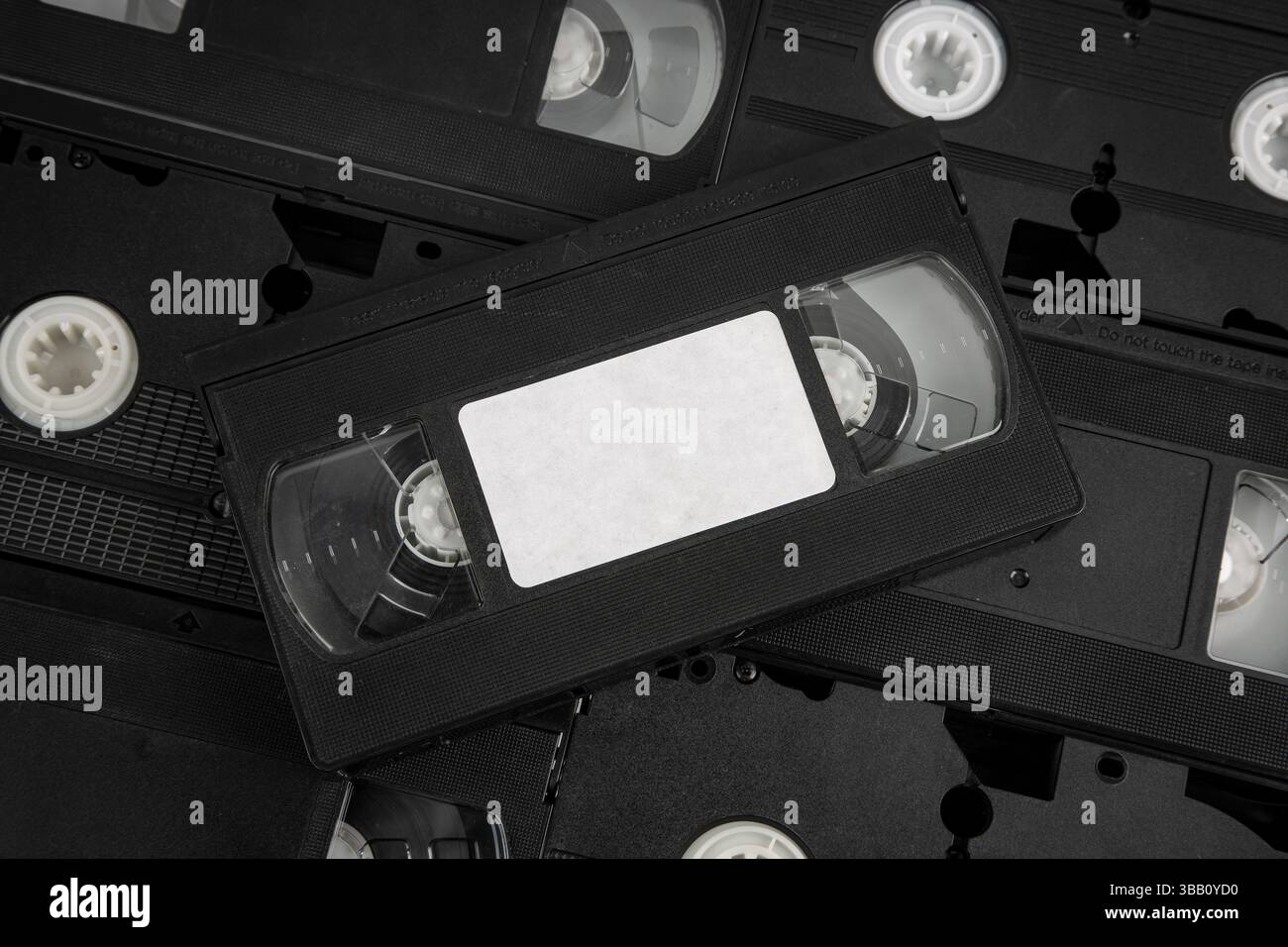 Stacked VHS tapes with a blank white label, black cassette, visible ...