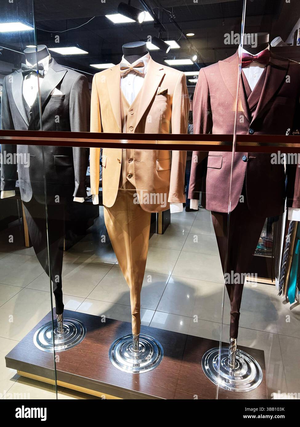 Three male mannequins dressed in formal suits displayed in a well-lit ...